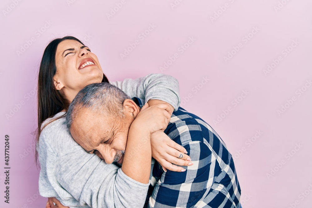 Young brunette woman and senior man standing over pink background ...