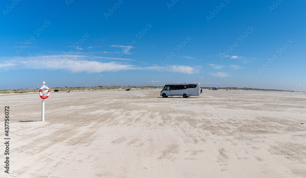 large RV parked on an endless golden sandy beach on the Wadden Sea ...
