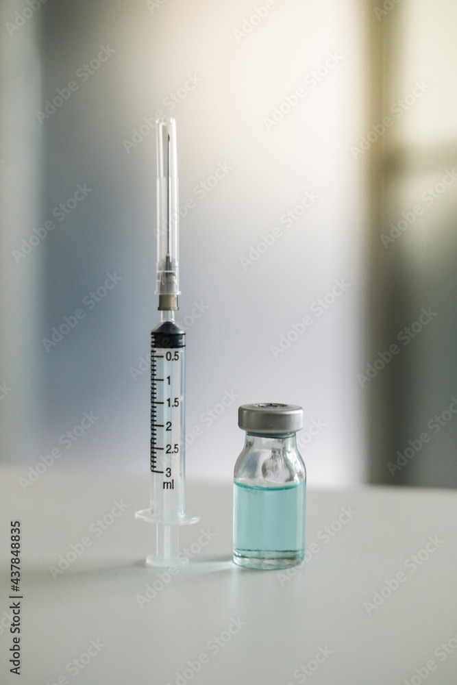 Vials with medication and syringe on white methacrylate table with ...