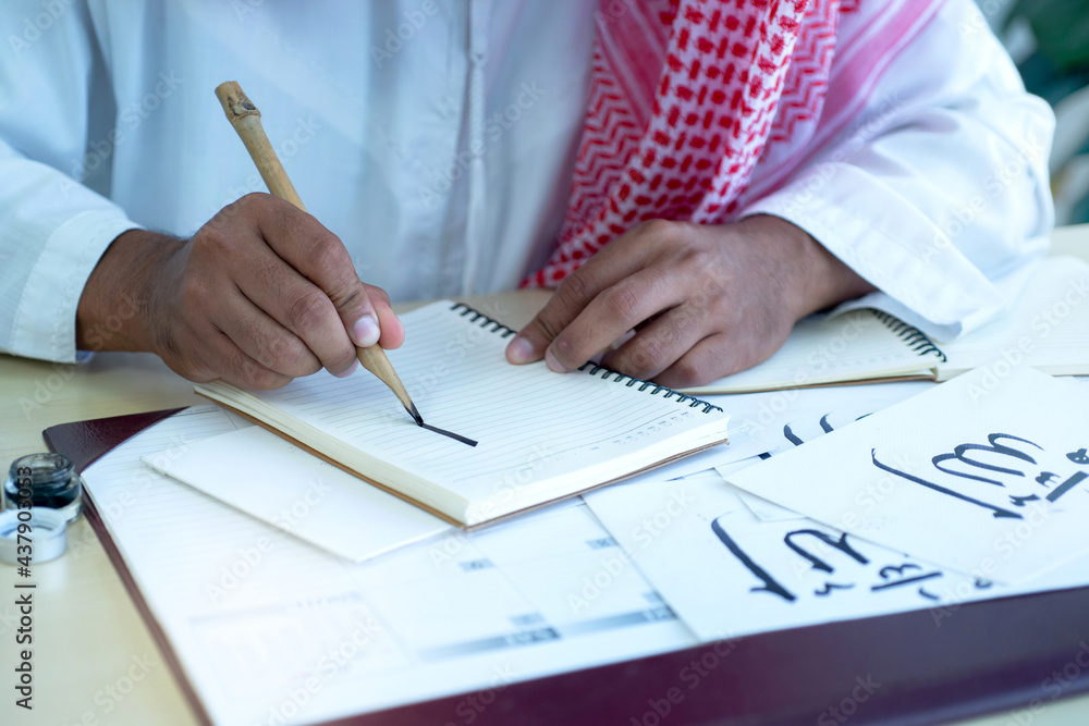 Arab men practicing writing Arabic ้with bamboo pens and ink on paper ...
