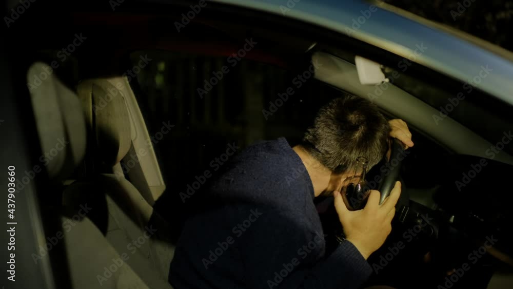 Drunk driver with empty alcohol bottle in hand puts head on steering ...