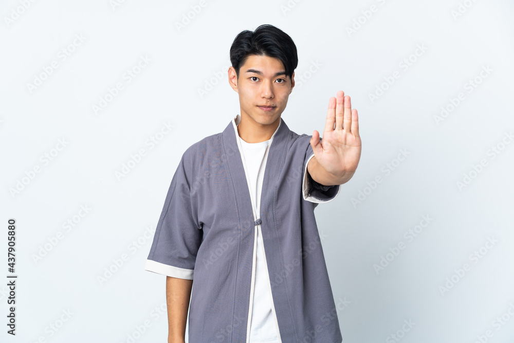 Young Chinese man isolated on white background making stop gesture ...