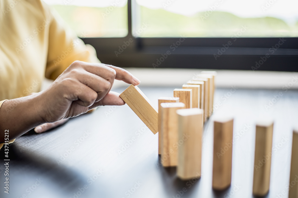 Businesswoman picking up a block of wood from a row, solving problems ...