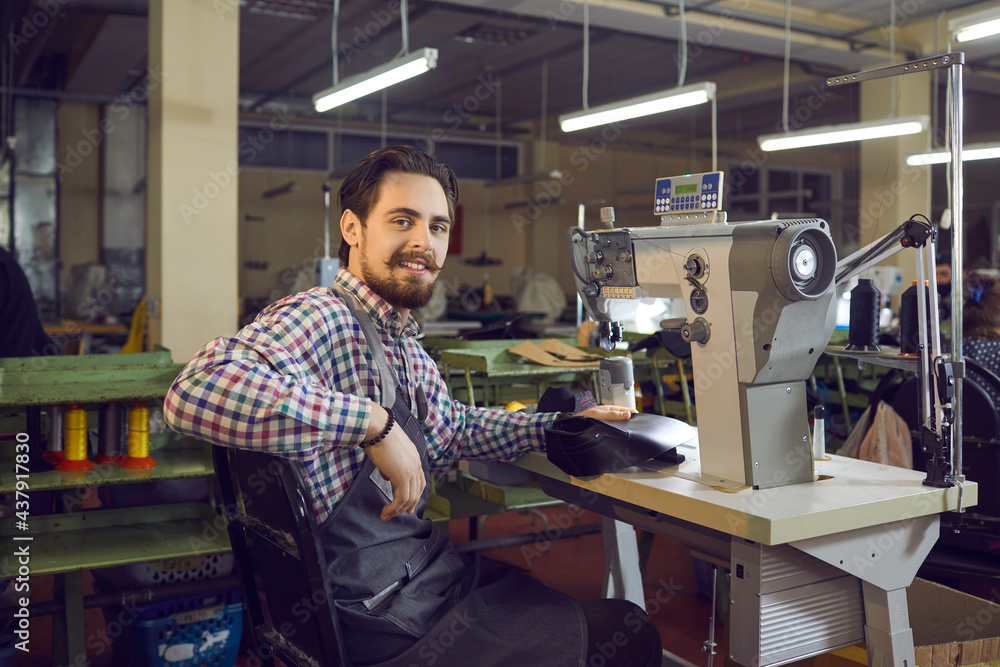 Portrait of happy smiling male shoemaker in apron working on sewing ...