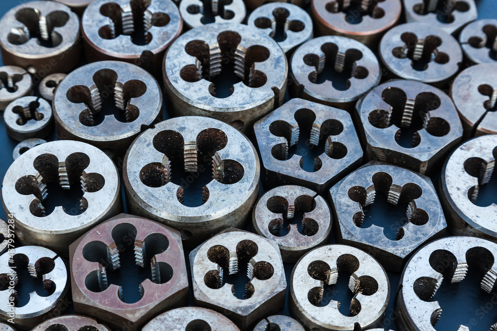 Bolt threading dies. Many dies of different sizes, top view. Hand tool ...