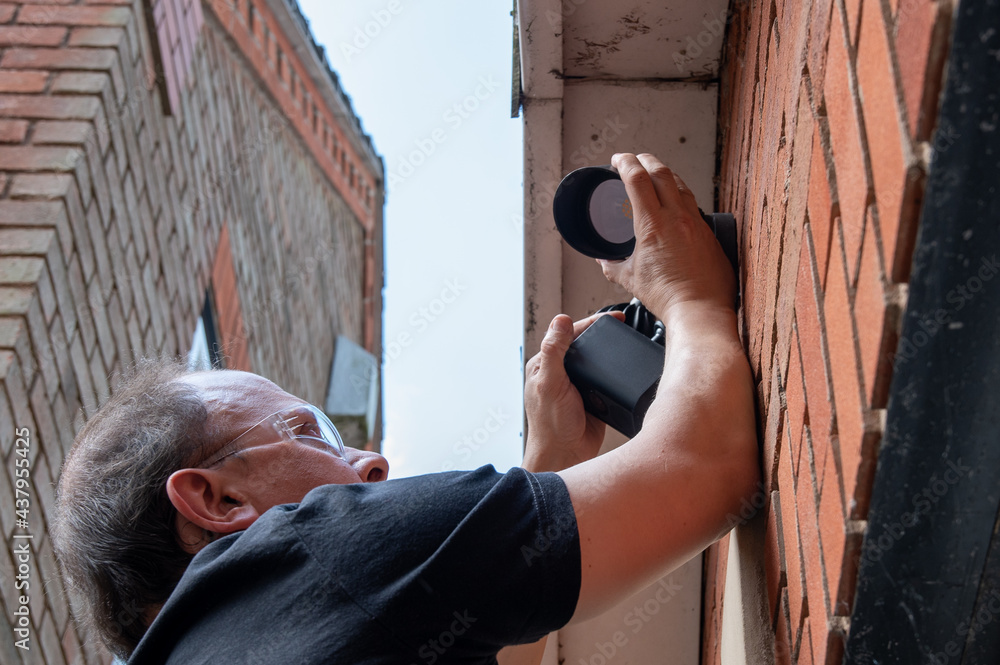 Man adjusting a spotlight and wireless security camera installed on the ...
