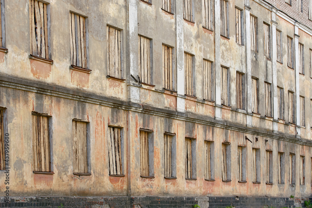 Facade of old building with many clogged windows and rough plaster ...