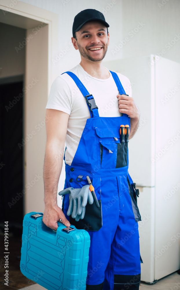 Professional young repairman in worker uniform and cap with modern ...