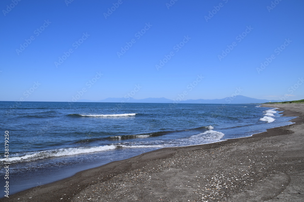 Landscape of black sand beach facing Sea of Okhotsk and far view of ...