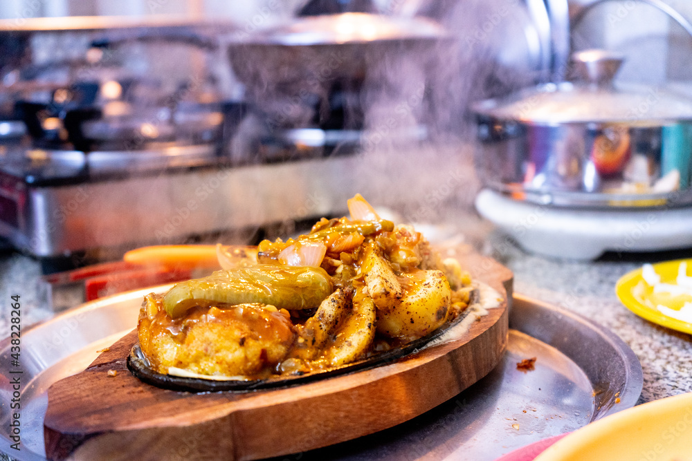 Indian asian sizzler dish served on a wooden tray with an iron hot ...