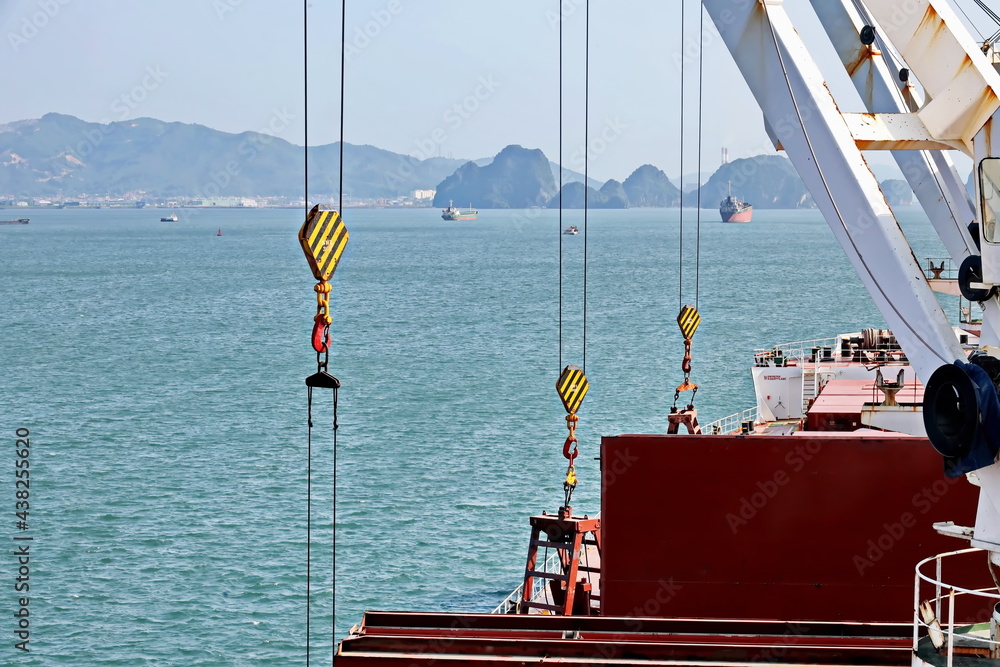 Loading bulk cargo of limestone from barges into a bulk carrier by ...