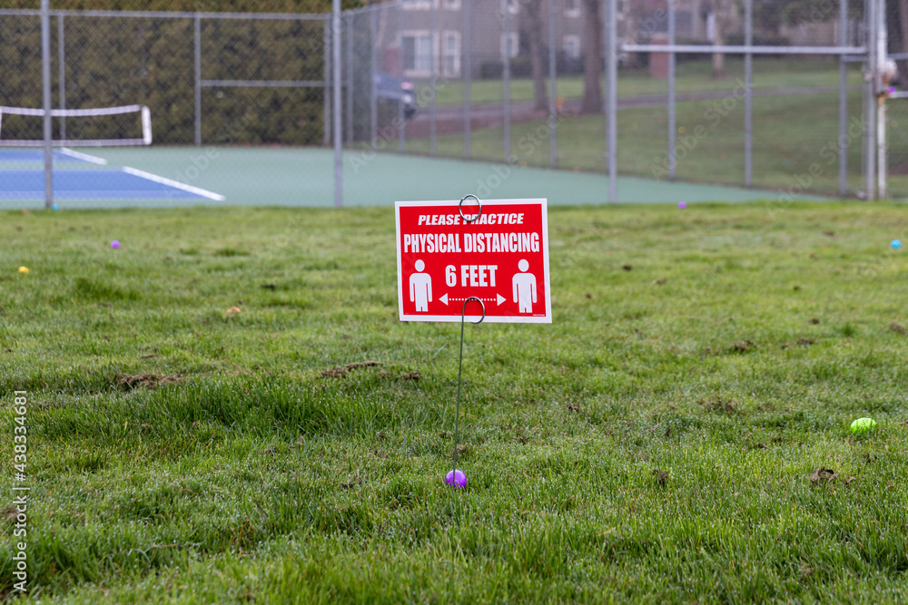 A red posted sign in the middle of a green lawn read "Please practice ...