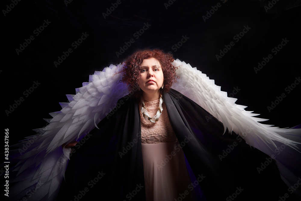 A brunette curly girl in black dress looking like an evil angel with ...