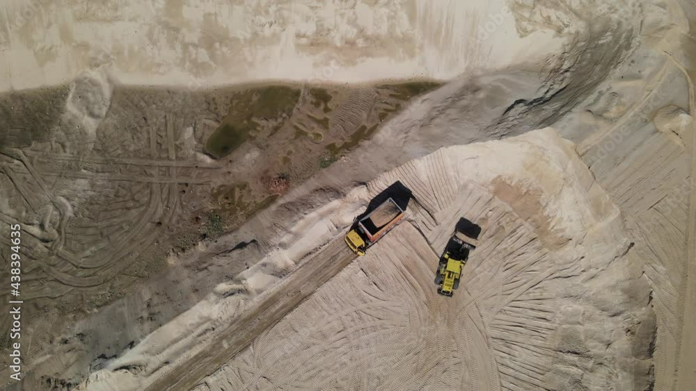 Front end loader loading sand into dump truck in open pit mine. Wheel ...