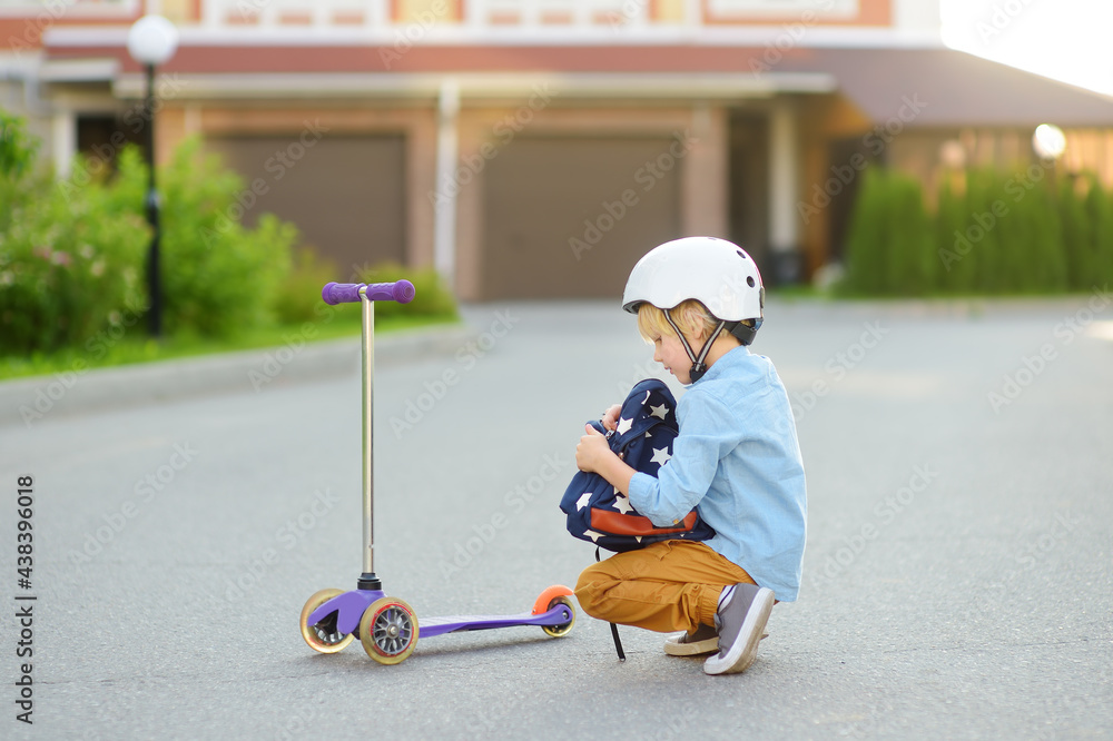 Little boy in safety helmet is riding scooter to school. Quality ...