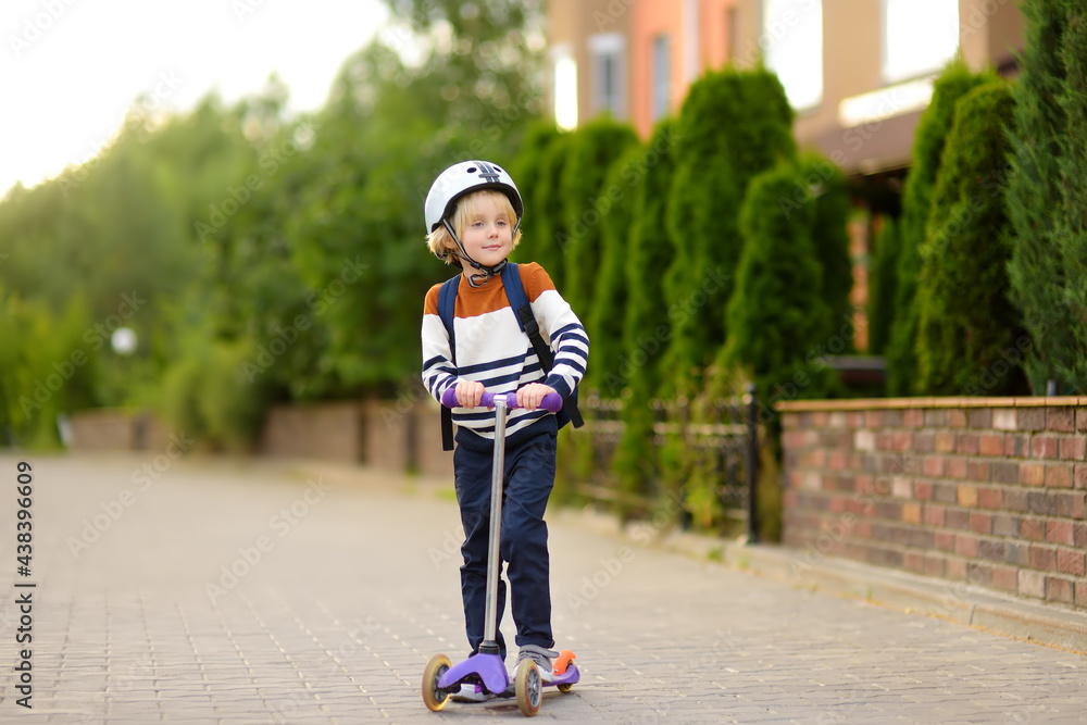 Little boy in safety helmet is riding scooter to school. Quality ...