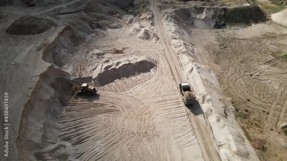 Wheel loader loading sand into dump truck in open pit mine. Arial view ...