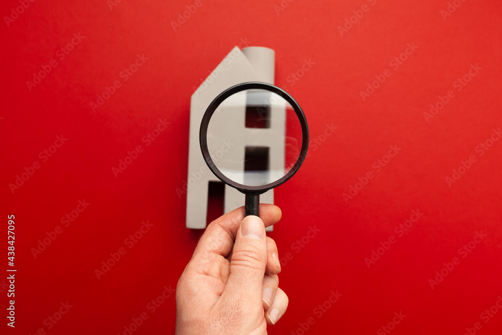 Housing inspection. A hand with a magnifying glass looks for flaws in a ...