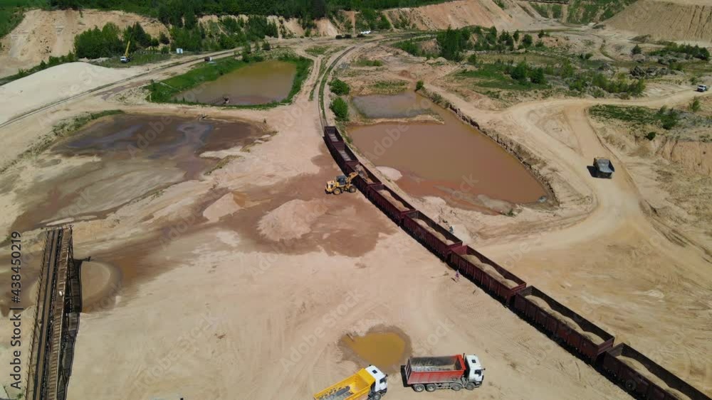 Front-end loader loading sand it to the freight train. Mining work in a ...
