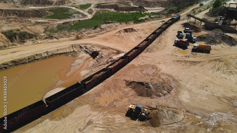Front-end loader loading sand it to the freight train. Mining work in a ...