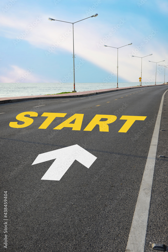 Start written on black asphalt road with white arrow and marking lines ...