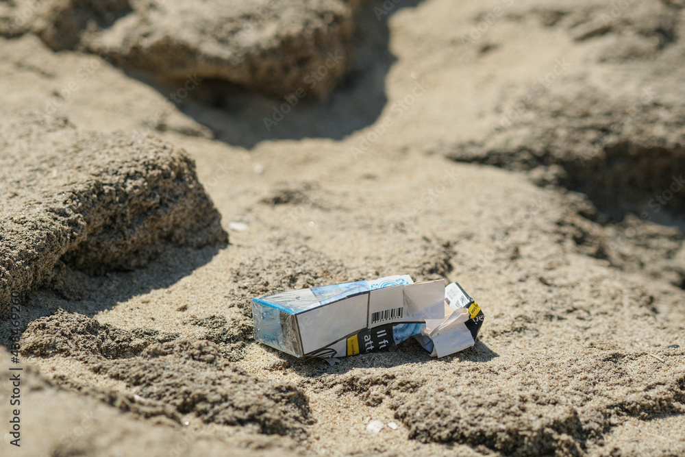 Dirty cigarette pack trash discarded on rocky sea coast ecosystem ...