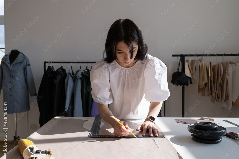 Female seamstress draw patterns for cutting, measure material on big ...