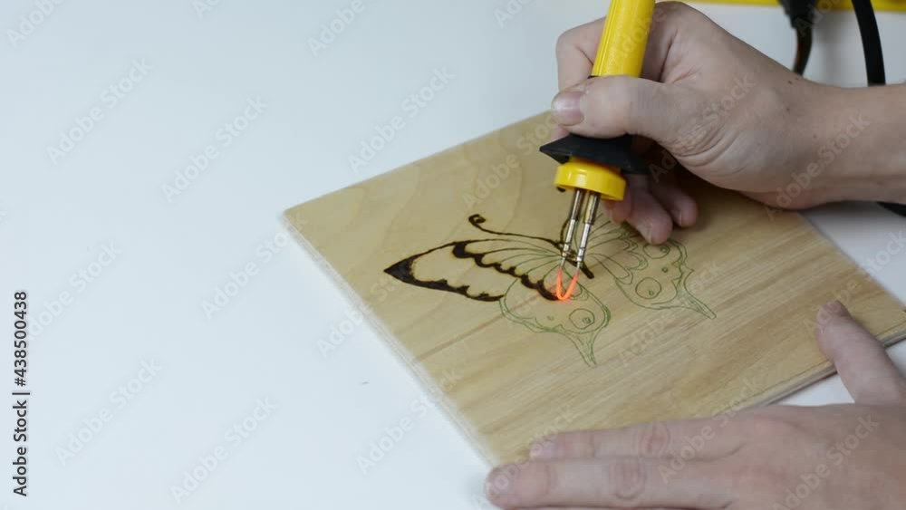 Drawing a picture on a tree using a burning device. A man's hand holds ...