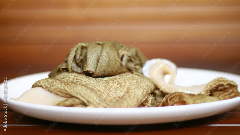 Beef tripe on white plate, wood background. Stock Photo | Adobe Stock