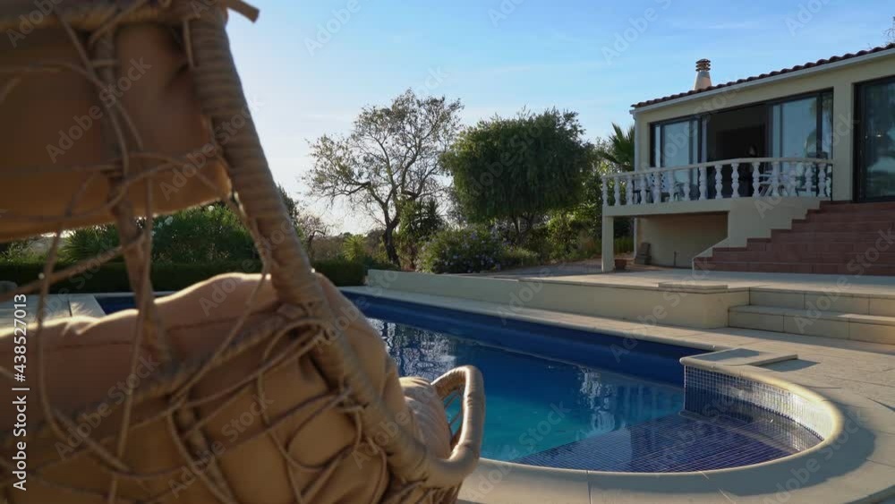 Vidéo Stock Luxurious hanging rocking chair, next to the clean pool and ...