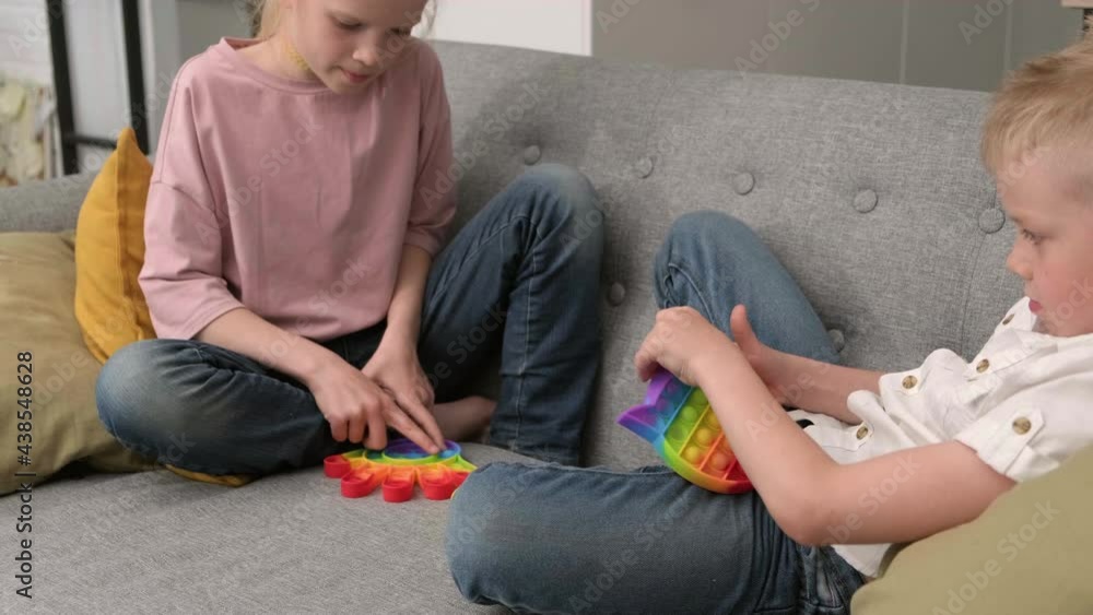 Kids playing with pop it sensory toy. boy and girl pressing on colorful ...