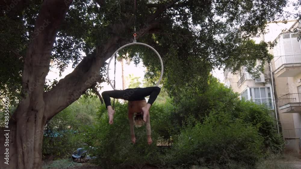 Acrobatic dancer balancing herself on an aerial ring hanging on her ...