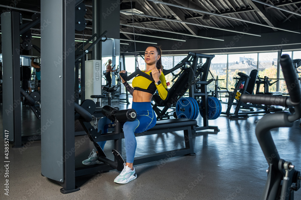 Girl training back muscles on pull-down machine in gym Stock Photo ...
