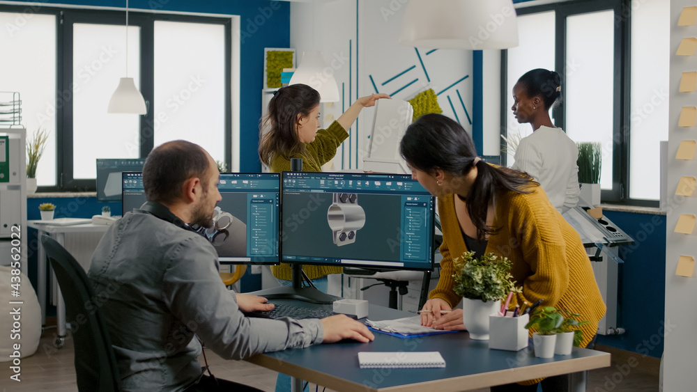 Team of engineers talking in front on pc with CAD software and two ...
