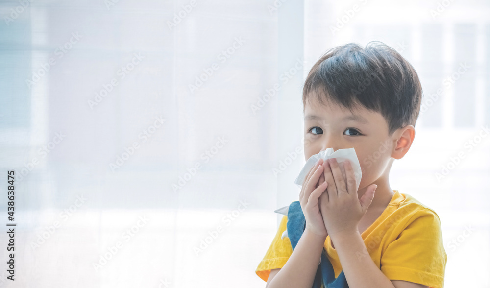 Little boy blowing nose into tissue paper and wearing surgical face ...