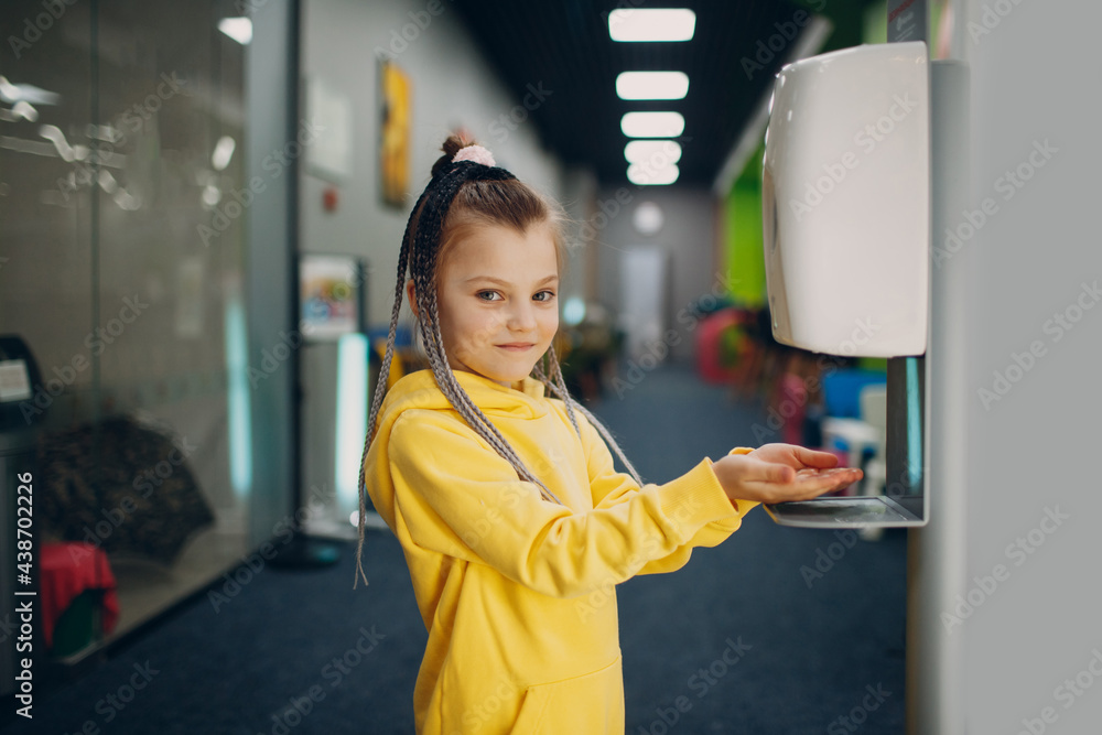 Little girl use automatic sanitizer with alcohol gel dispenser for ...