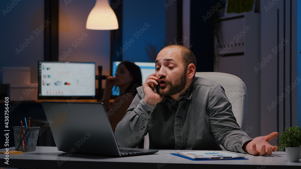 Stressed angry businessman sitting at desk table discussing corporate ...