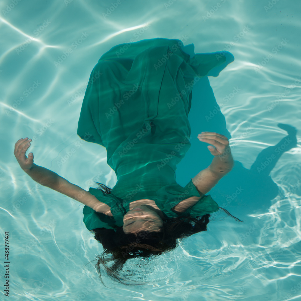 Girl in green dress floating under water in swimming pool Stock Photo ...