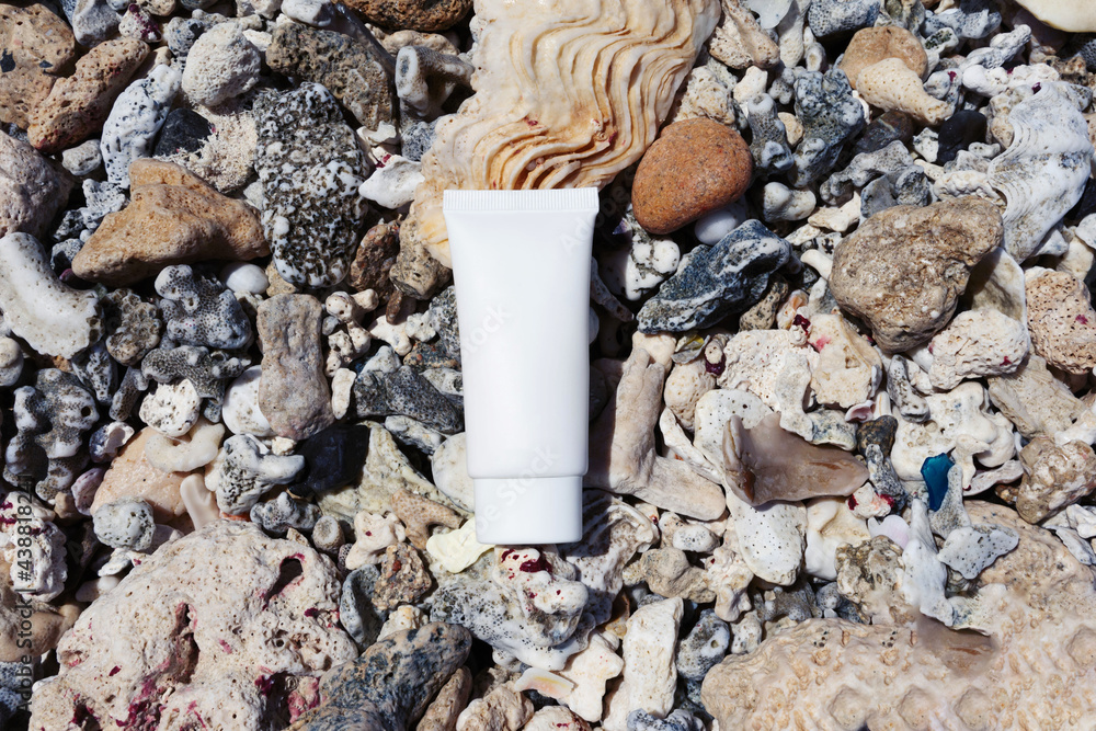 white cosmetic tube with sunscreen or lotion on a sea background dotted ...