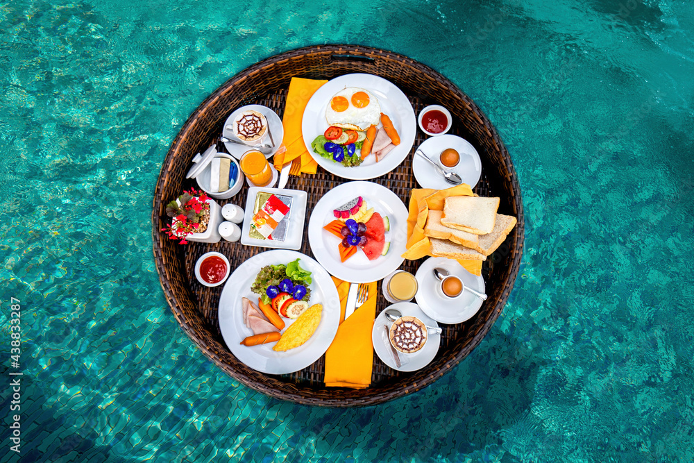 Set of floating breakfast tray in swimming pool with fried egg omelette ...