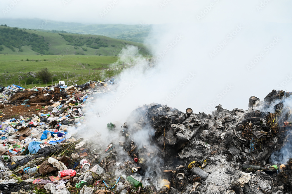 Foto de Open landfill site with burning waste. Burning pile of illegal ...
