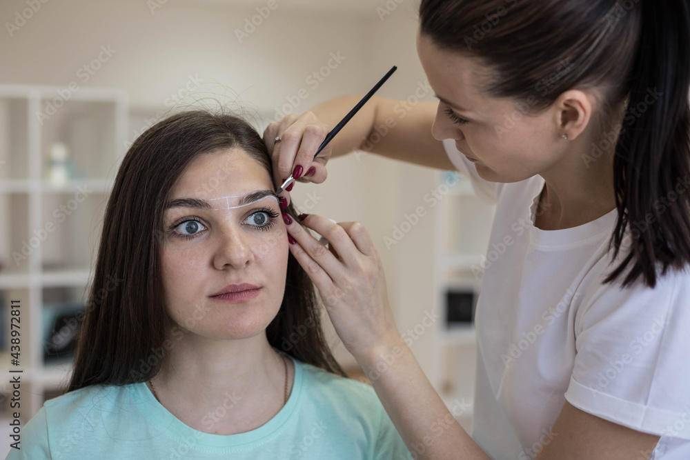 The master draws auxiliary lines between the eyebrows with a white ...