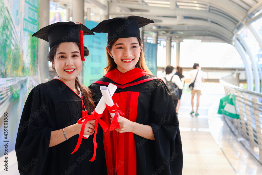 Portrait of two happy smiling graduated students holding certificate ...
