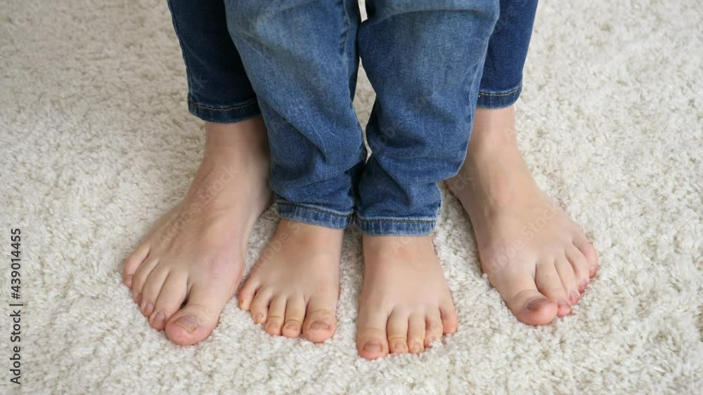 Closeup of female and child feet standing on soft carpet and moving ...