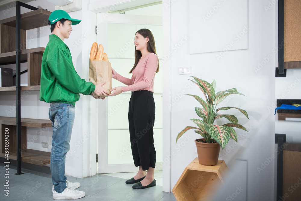 asian delivery man in green uniform handling bag of food, bread give to ...