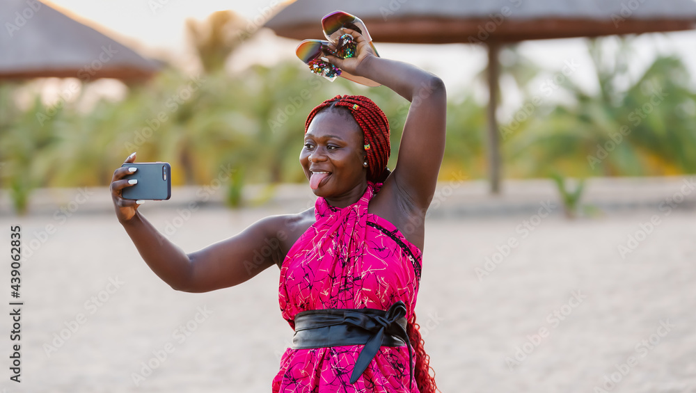 African woman standing on a tropical beach in Ghana working full time ...