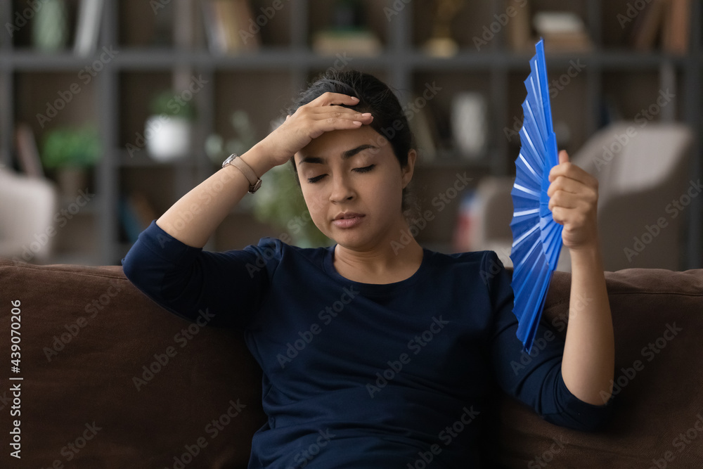 So hot. Frustrated young indian lady sit on sofa suffer from heat at ...