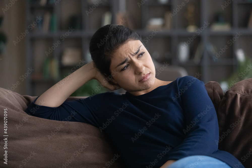 Melancholic mood. Sad depressed young indian woman sit on sofa at home ...