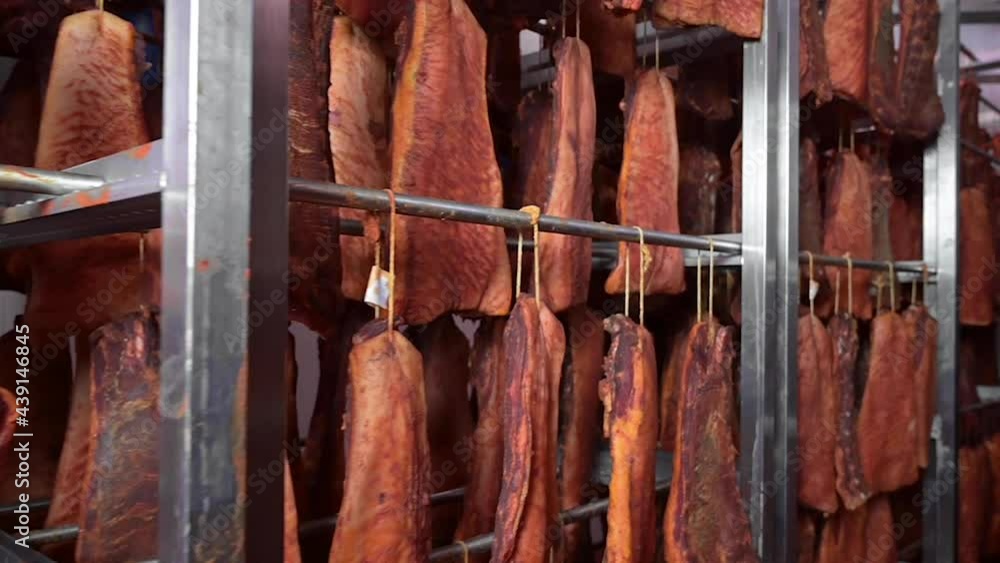 Cured meat hang from a rack at meat processing plant. Traditional food ...