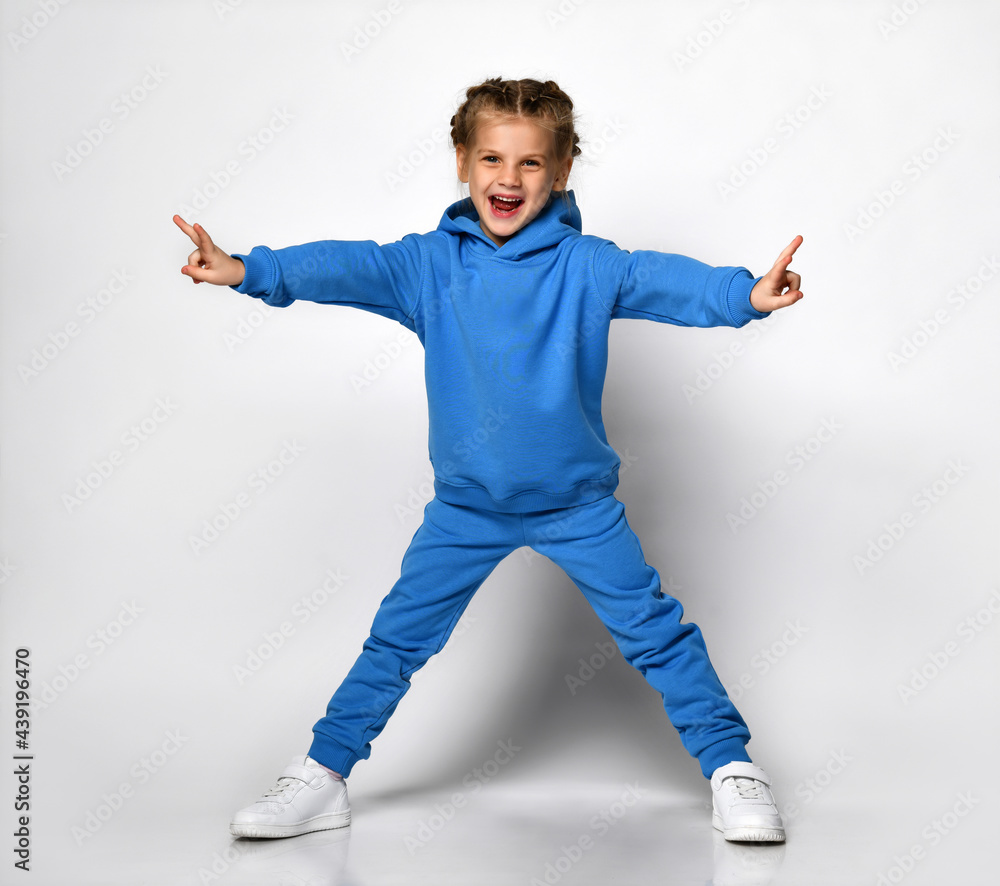 Active playful little girl in a trendy blue tracksuit having fun on a ...
